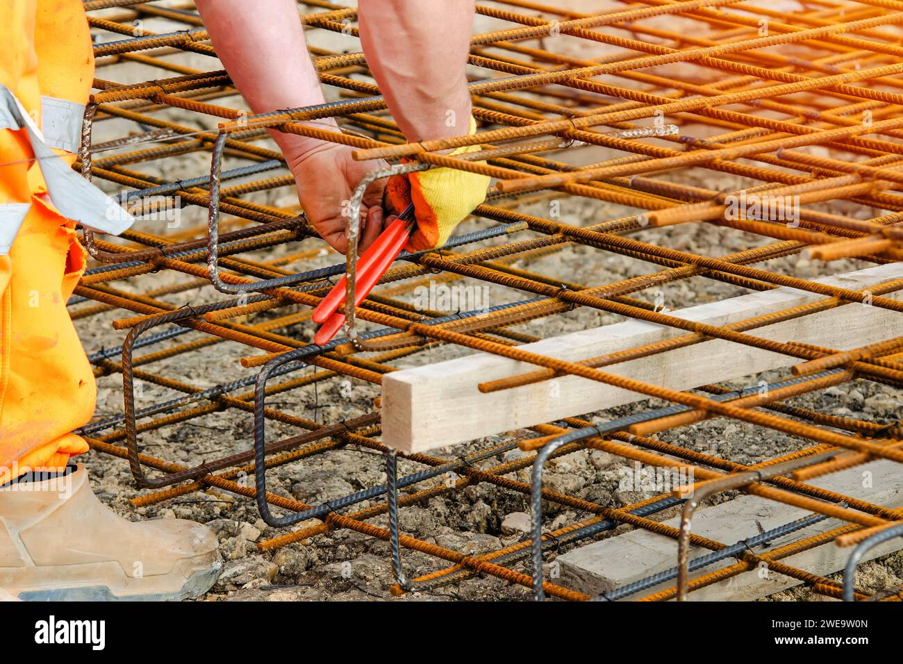 Steel fixer assembling reinforcement cage off rebars. Selective focus ...