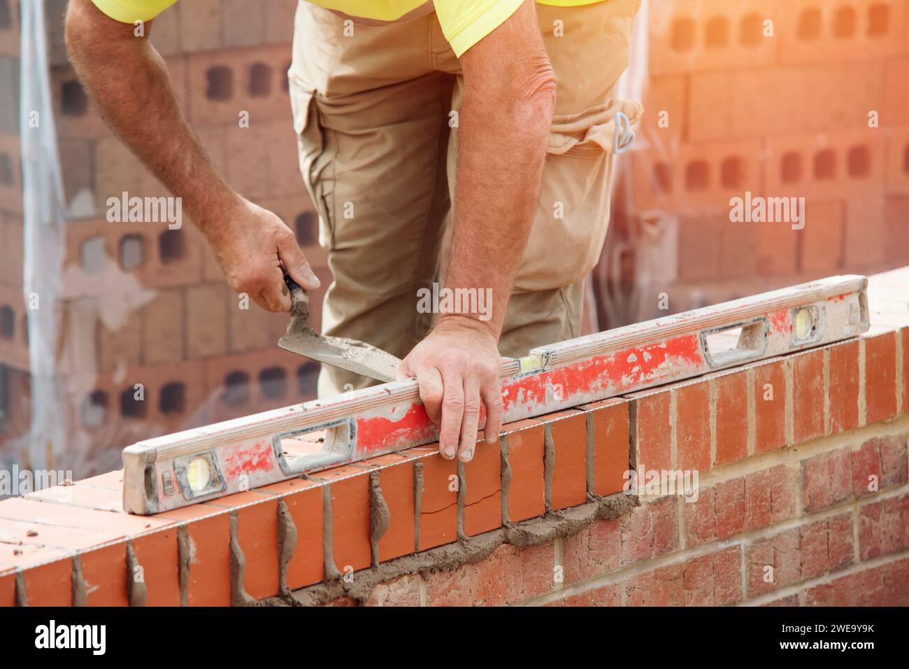 Close-up of an industrial bricklayer laying bricks on cement mix and ...