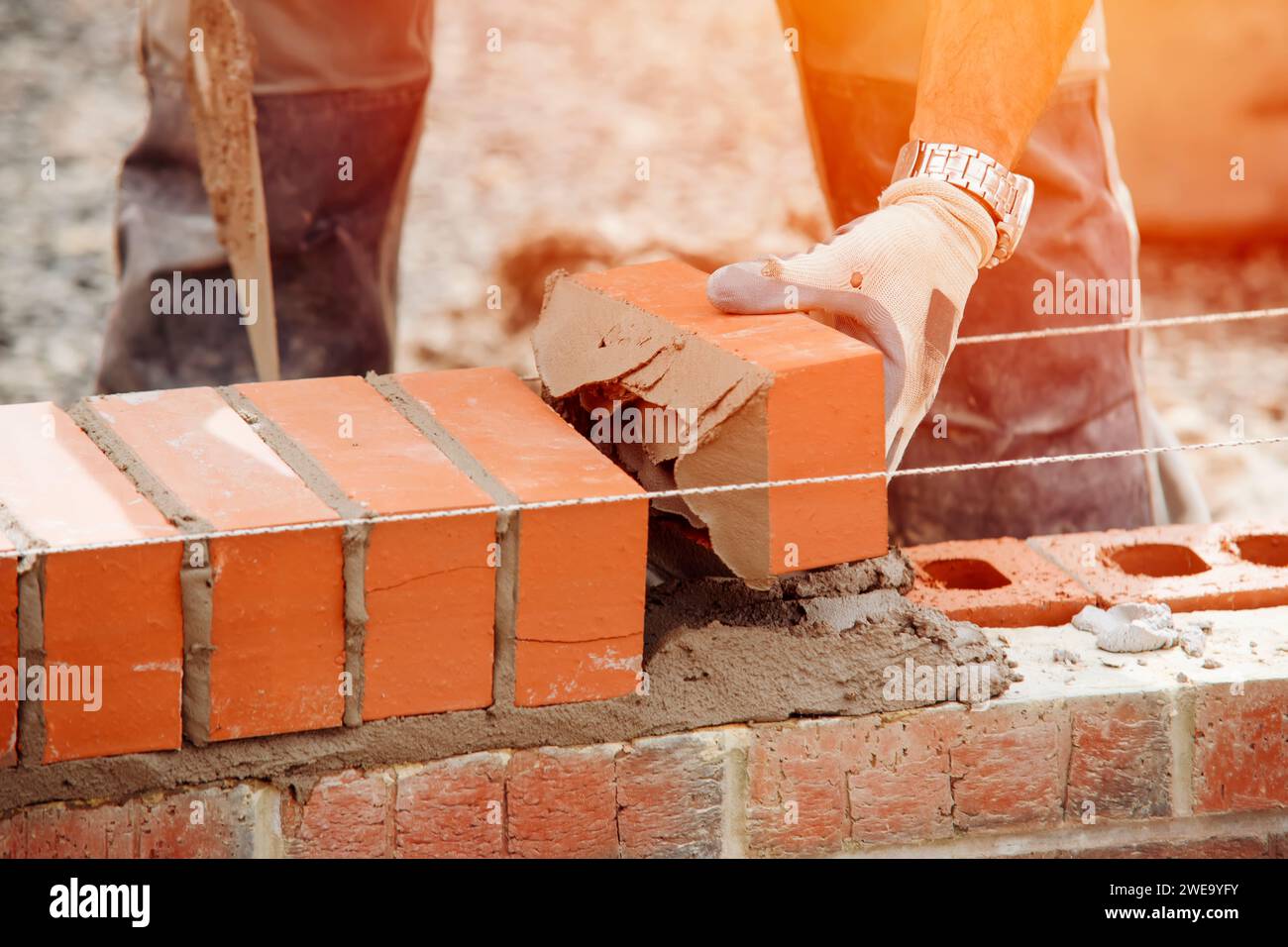 Industrial bricklayer laying bricks on cement mix on construction site ...