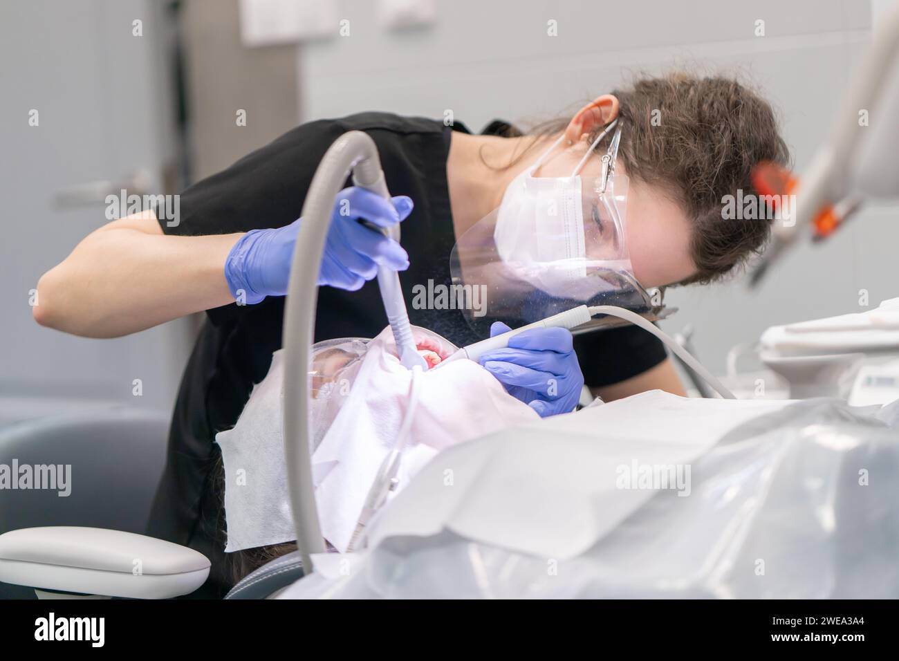 A dentist cleans the teeth from plaque and tartar using an air abrasion ...