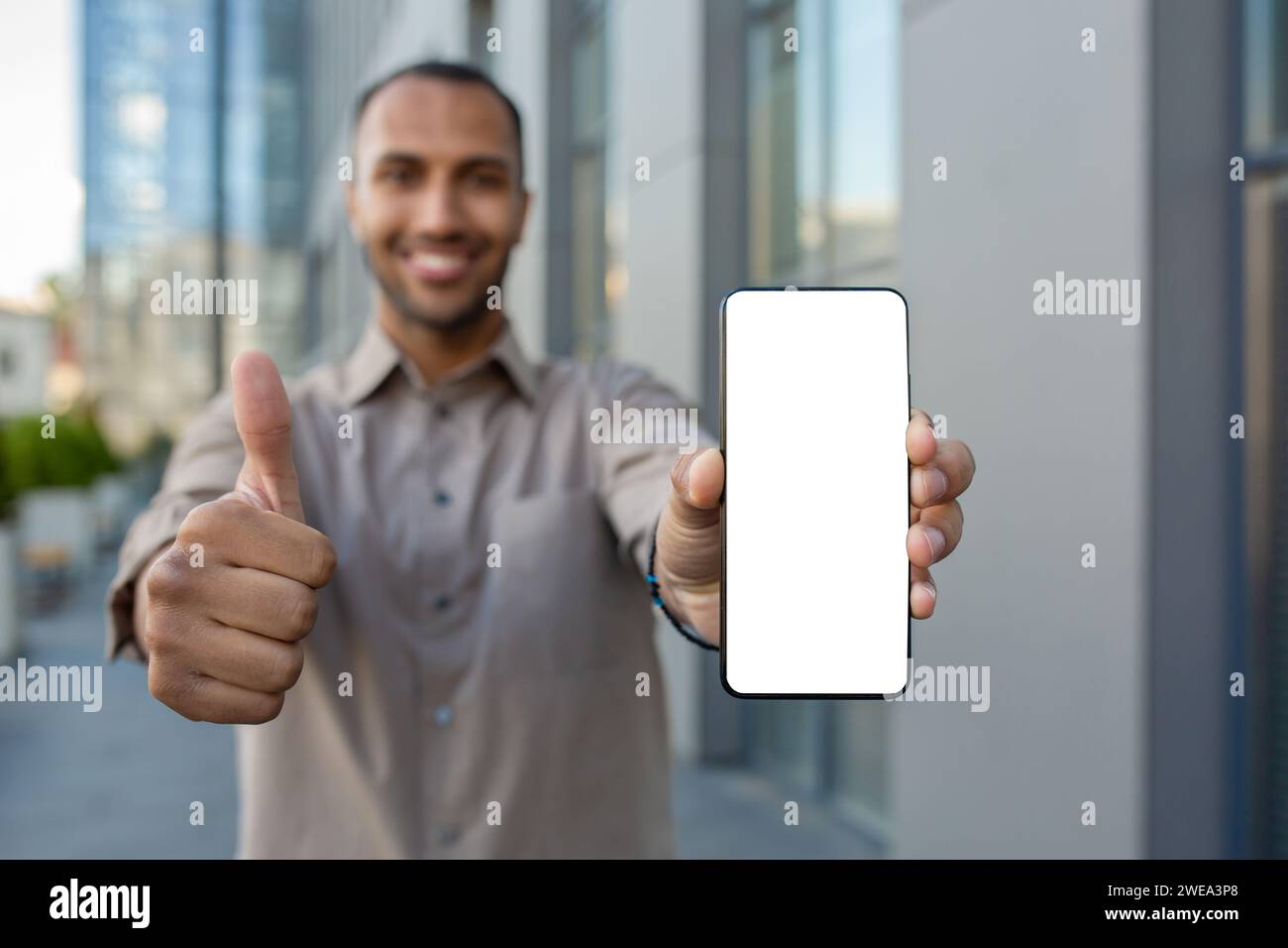 Young successful man showing white phone screen to camera, businessman ...