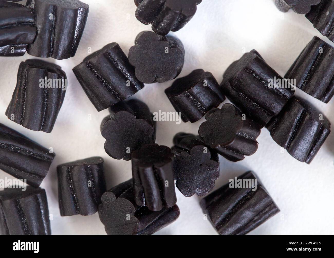 Pieces of black licorice sweets scattered on plain white surface Stock ...