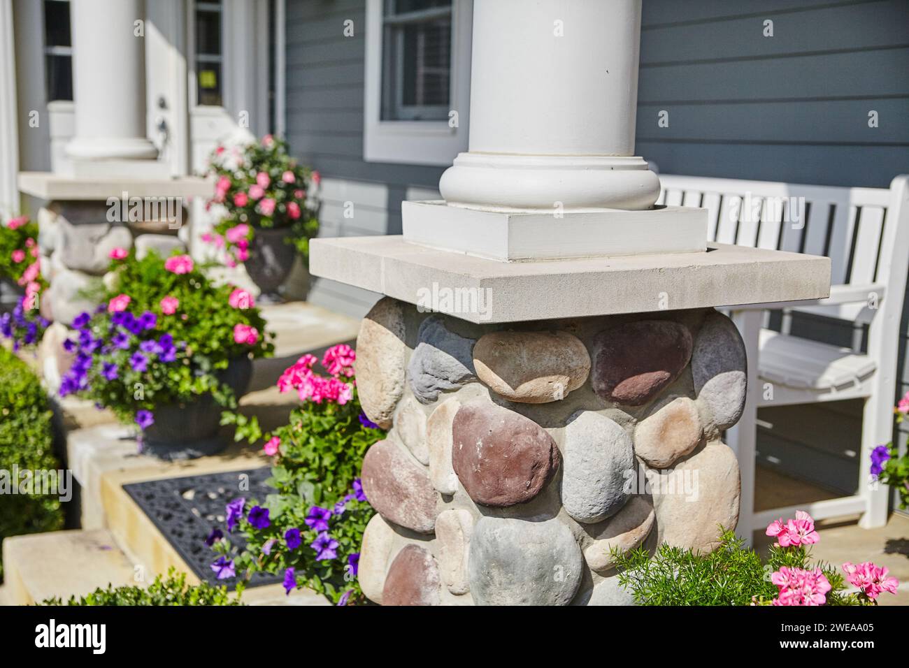 Sunny Residential Entrance with Stone Column and Flower Arrangements ...
