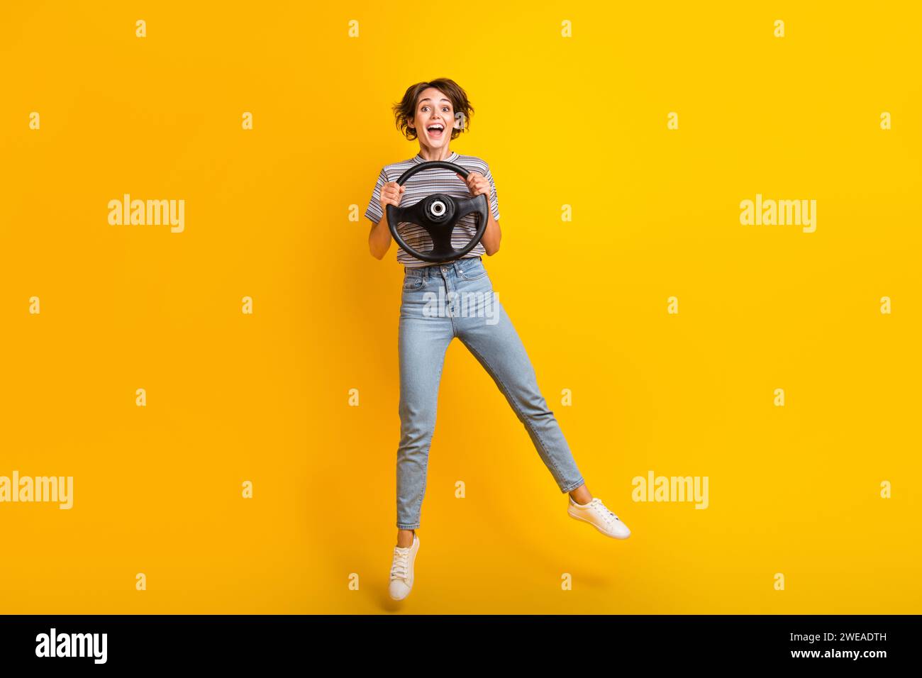 Full body photo of overjoyed cheerful lady jumping arms hold wheel ...