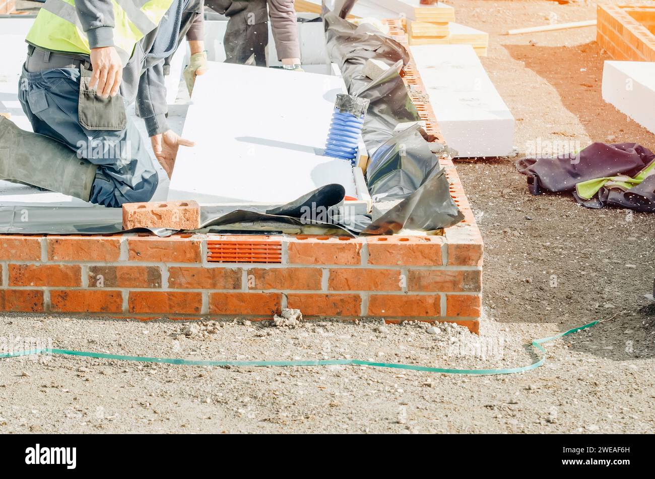 Builder placing polystyrene insulation boards on waterproofing membrane ...