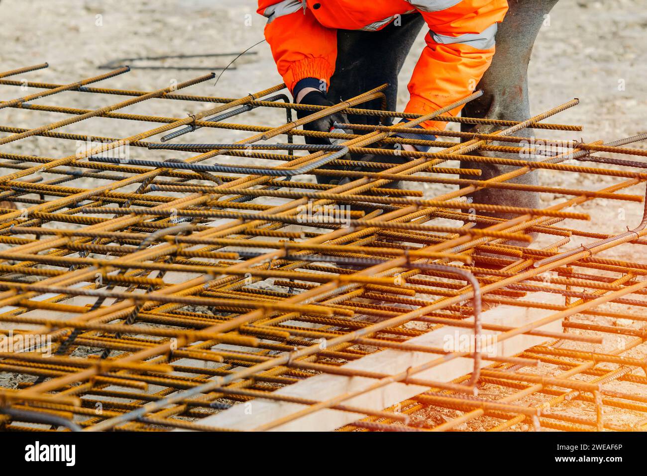 Steel fixer assembling reinforcement cage off rebars. Selective focus ...