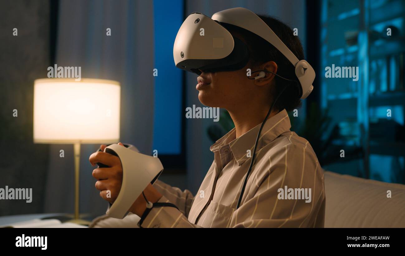 African American girl woman in VR helmet augmented reality glasses metaverse gaming simulation ...