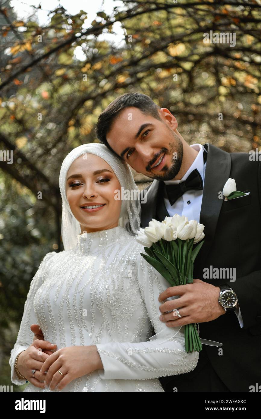 Young bride and groom with tulip bouquet looking at camera smiling and ...