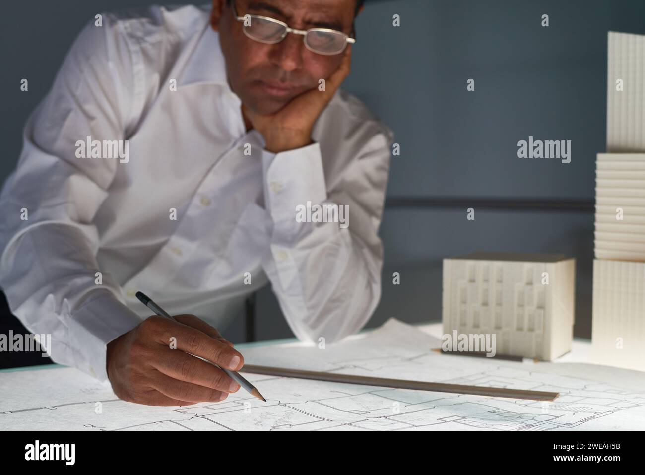 Close up of male Indian architect drawing plans at backlight ...