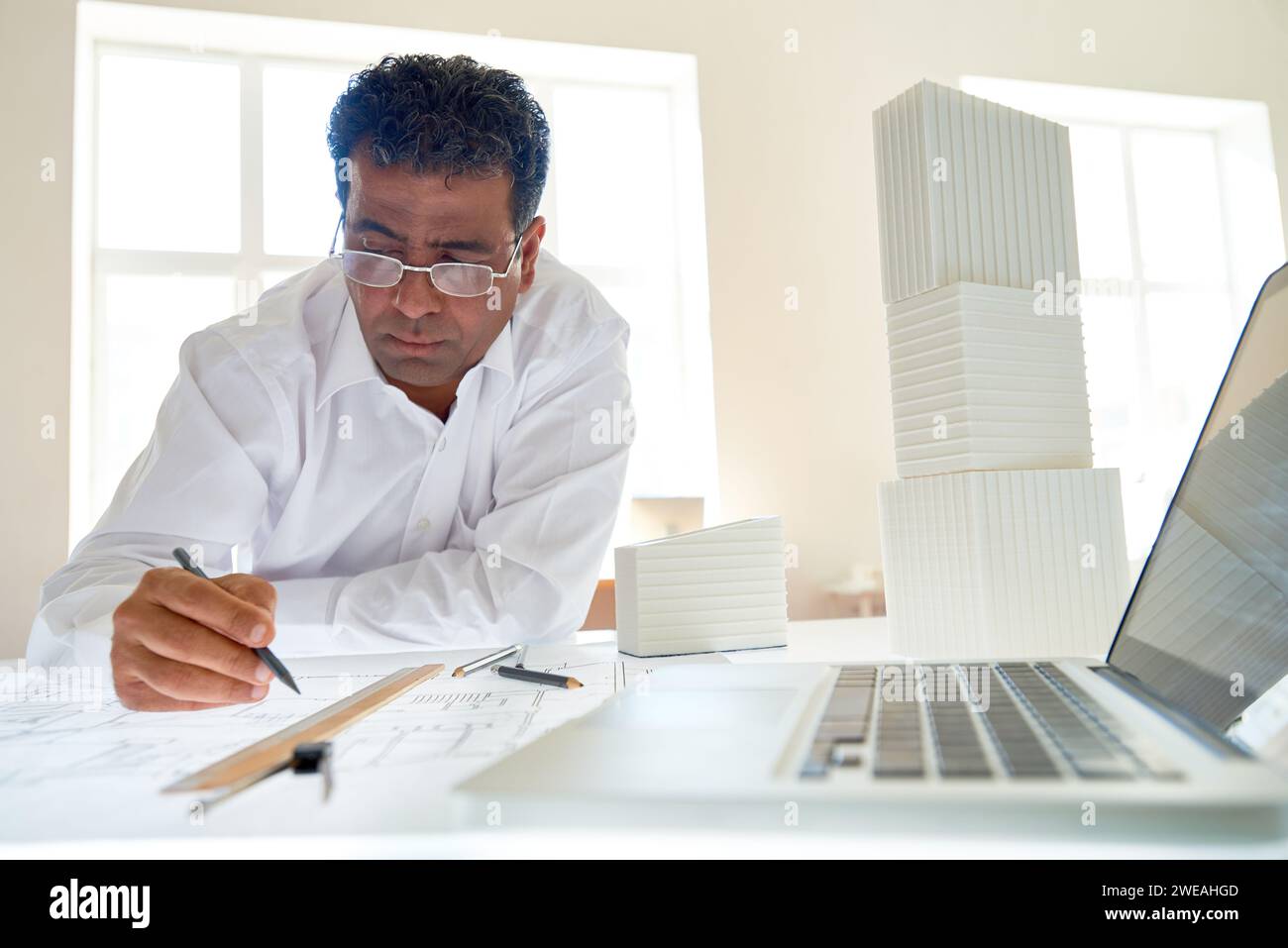 Front view portrait of mature Indian architect at workstation in office ...