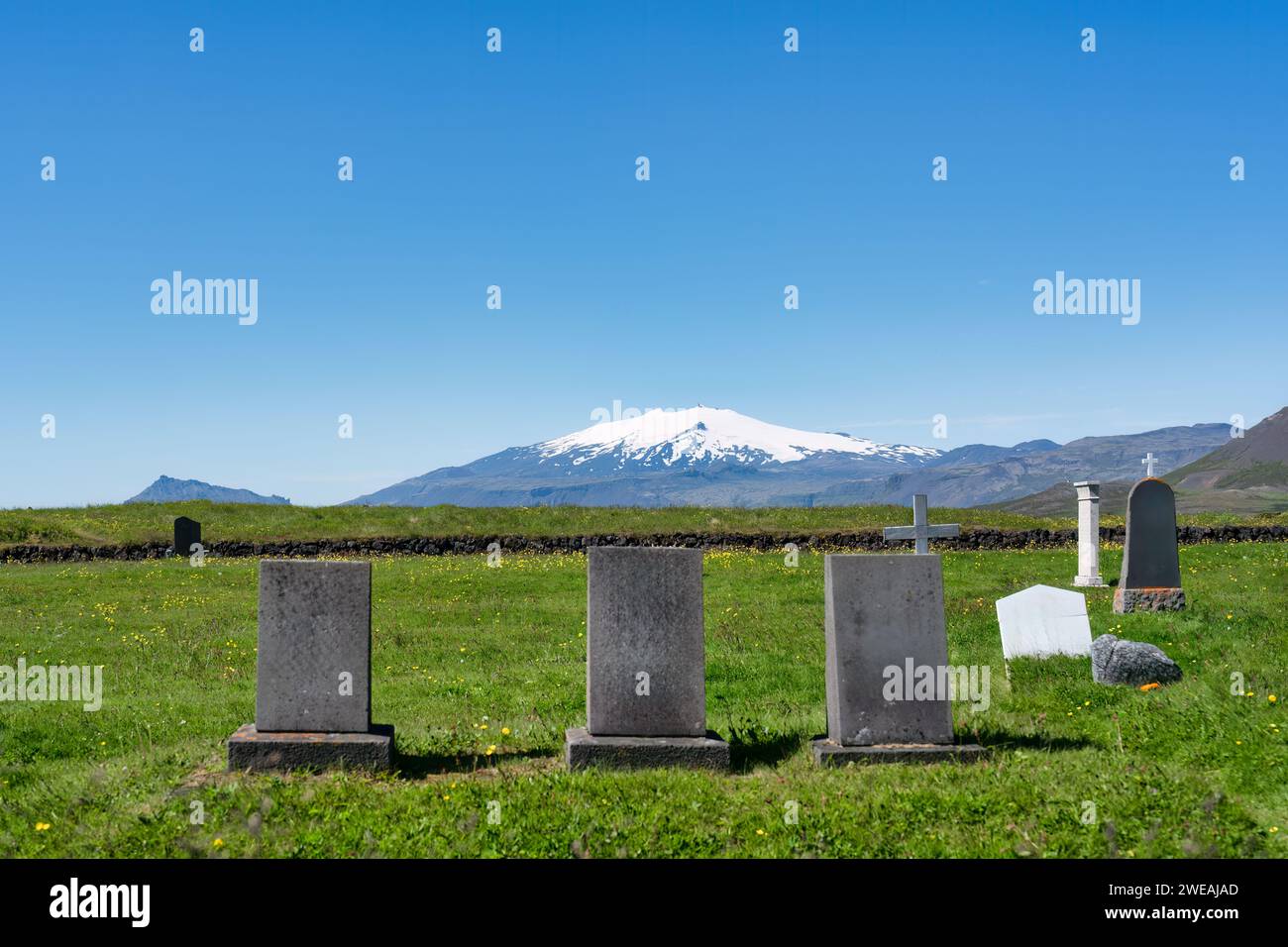 Gravestone on grass in Christian church cemetery and volcanic mountain ...