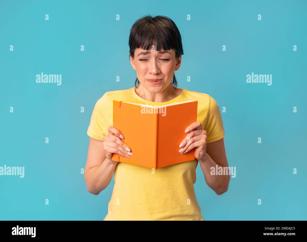 Sad woman student holding open book isolated portrait on blue ...
