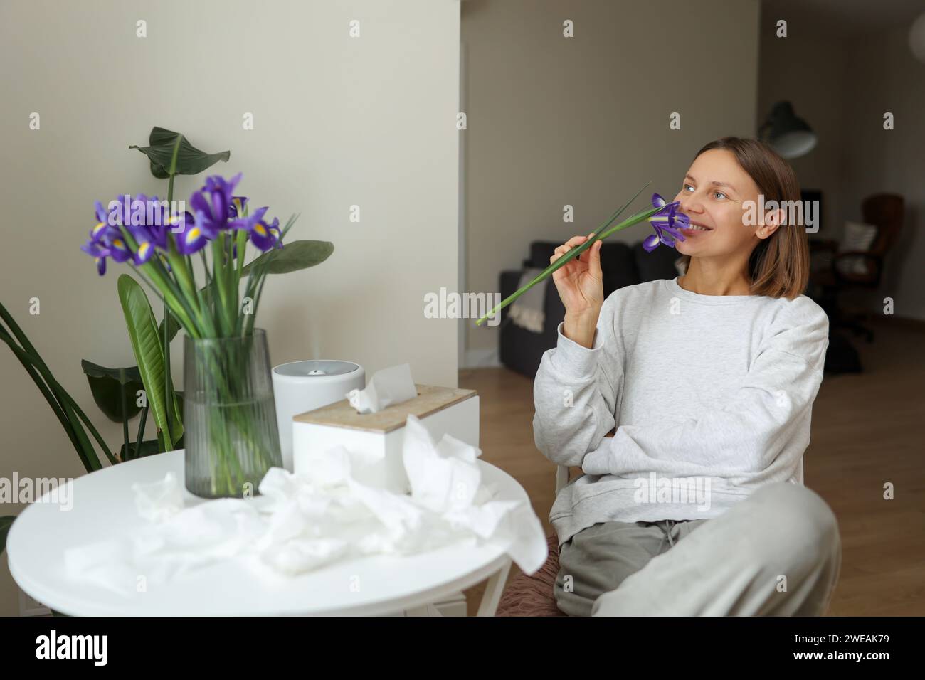 Allergy free. Beautiful young woman holds and sniffs iris flower ...