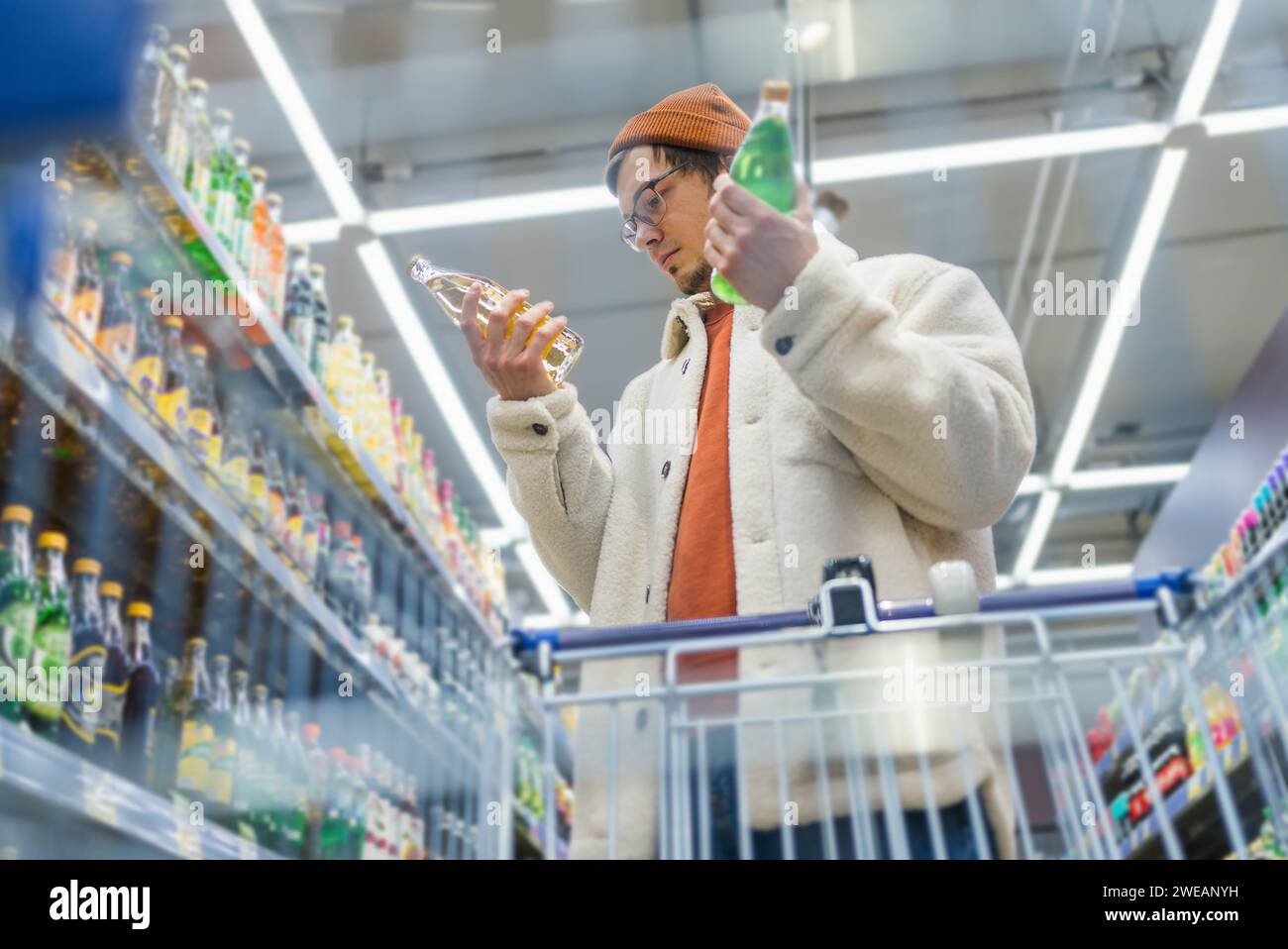 Man in store chooses drink. Guy in supermarket reads label, composition ...