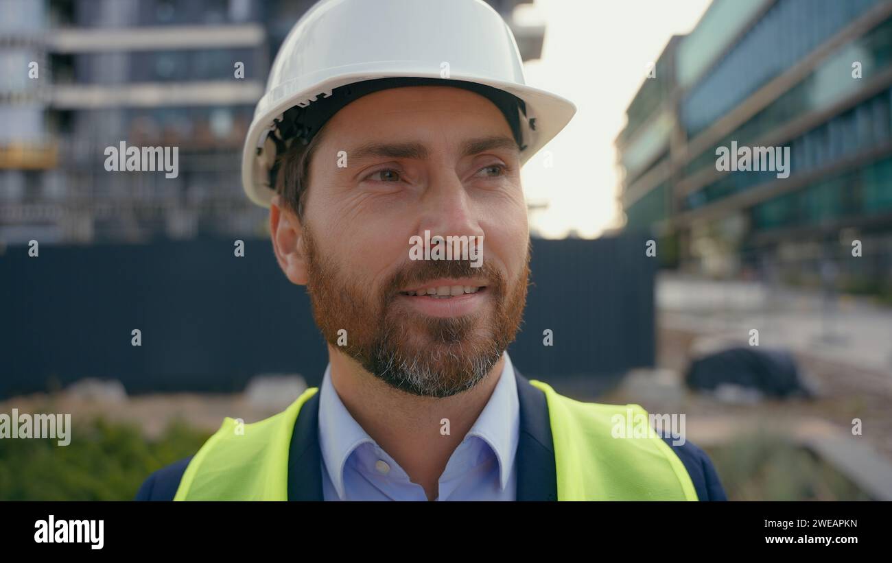 Portrait close up man worker repairman in safety helmet looking around smile male contractor ...