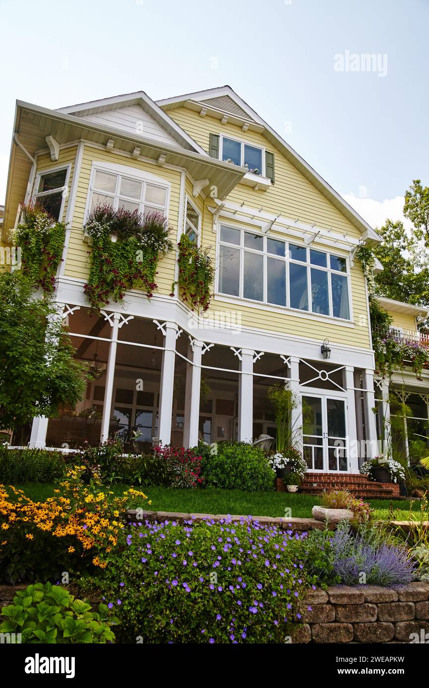 Charming Yellow Victorian-Style House with Lush Garden and Porch Stock ...
