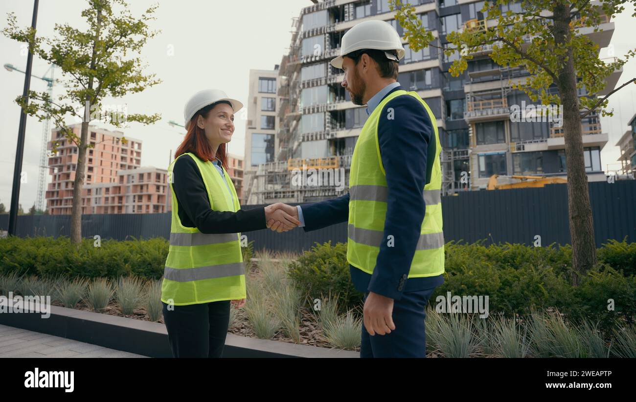 Two people colleagues in safety uniform helmets hardhat engineers ...
