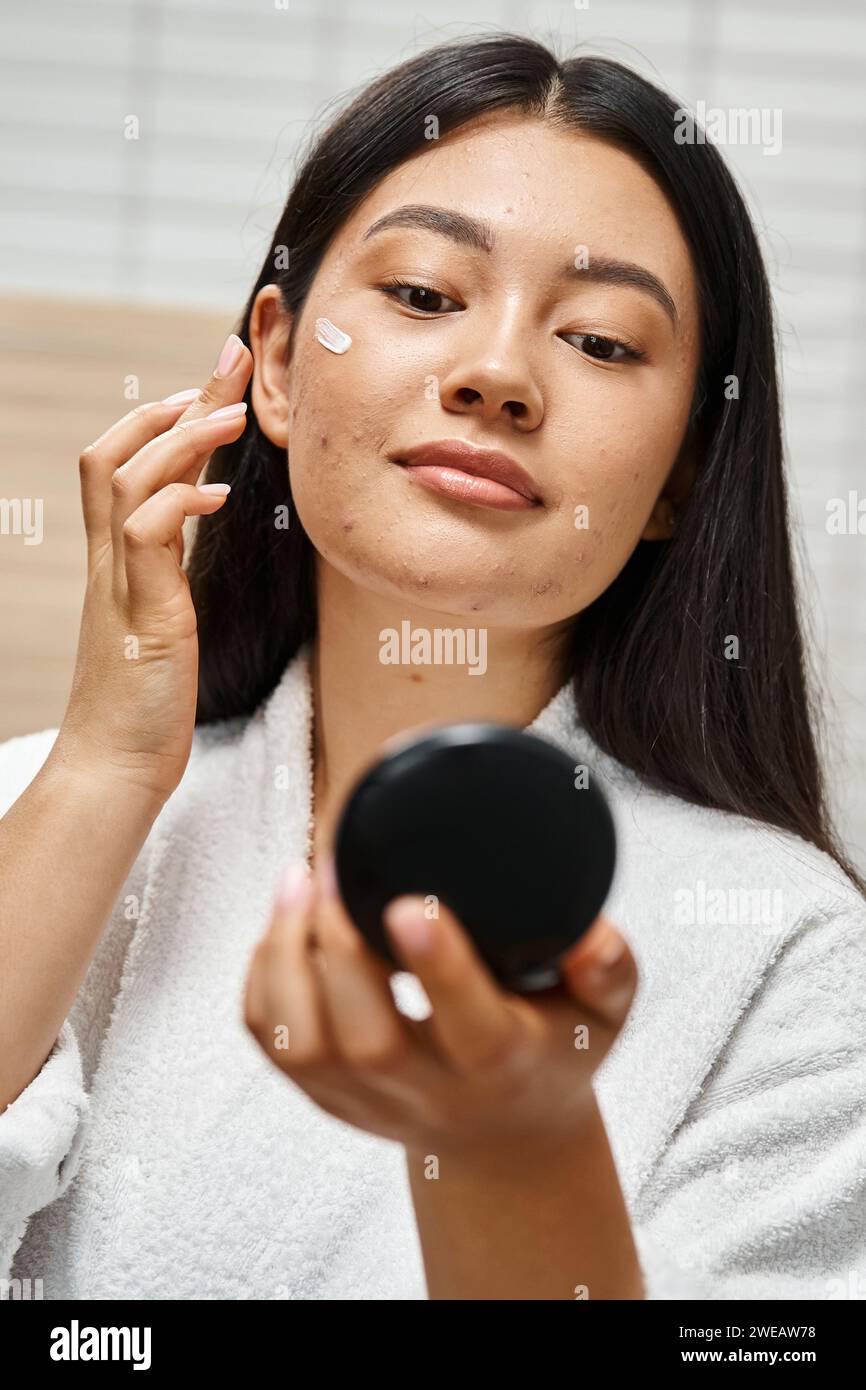 blemish treatment cream on face of young asian woman with acne looking ...