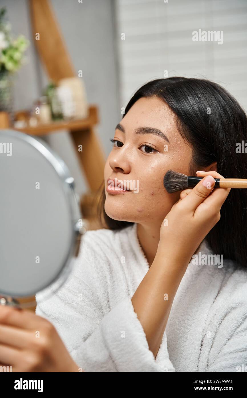 young asian woman with brunette hair and acne on skin applying face ...
