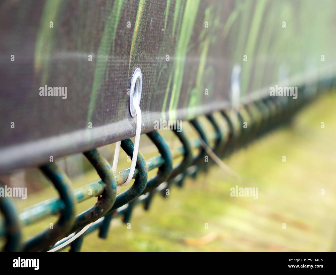 Attaching a banner to a mesh fence with zip ties Stock Photo - Alamy