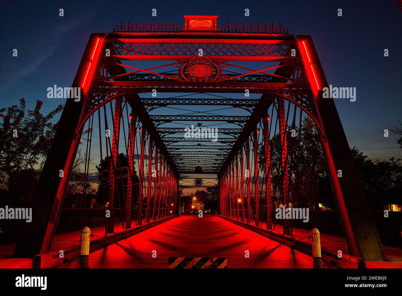 Red-Lit Truss Bridge at Twilight with Urban Backdrop Stock Photo - Alamy