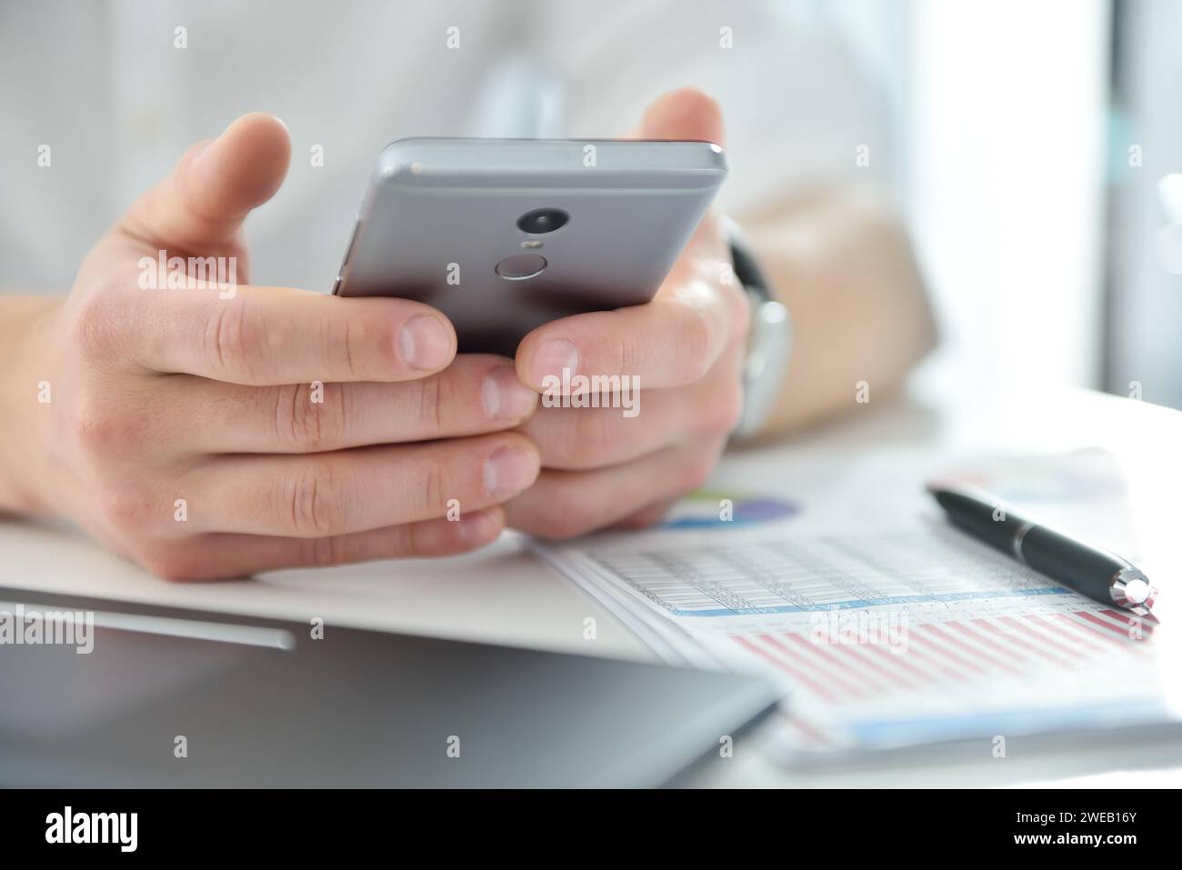 Manager sitting in office and writes message on smartphone. Business ...