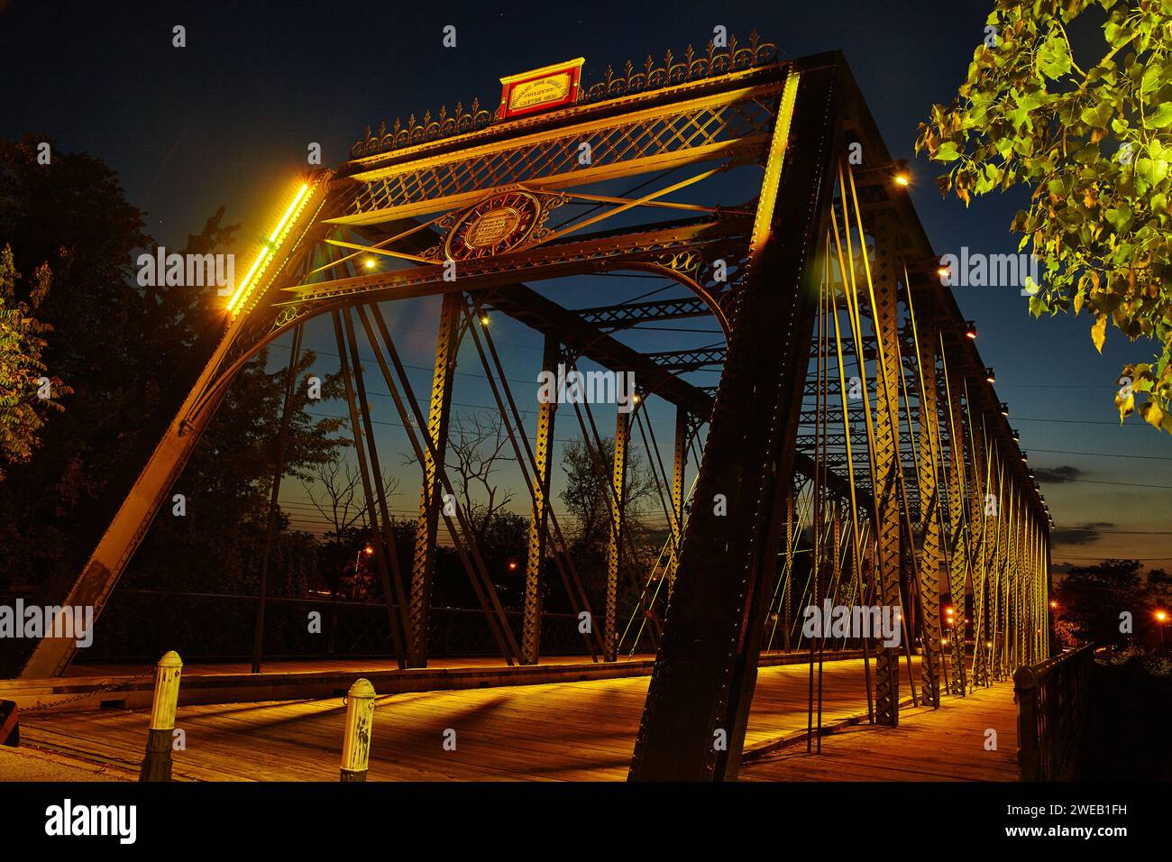 Illuminated Truss Bridge at Blue Hour, Warm Glow on Walkway Stock Photo ...