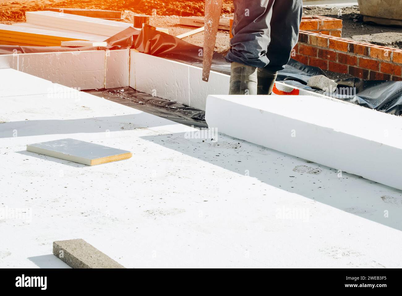 Builder placing polystyrene insulation boards on waterproofing membrane ...