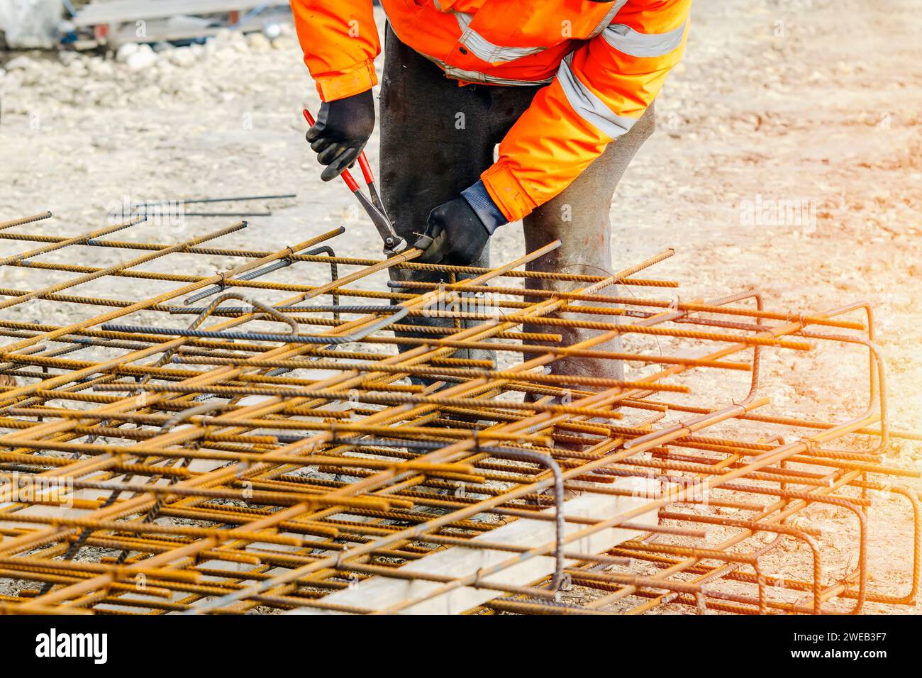 Steel fixer assembling reinforcement cage off rebars. Selective focus ...