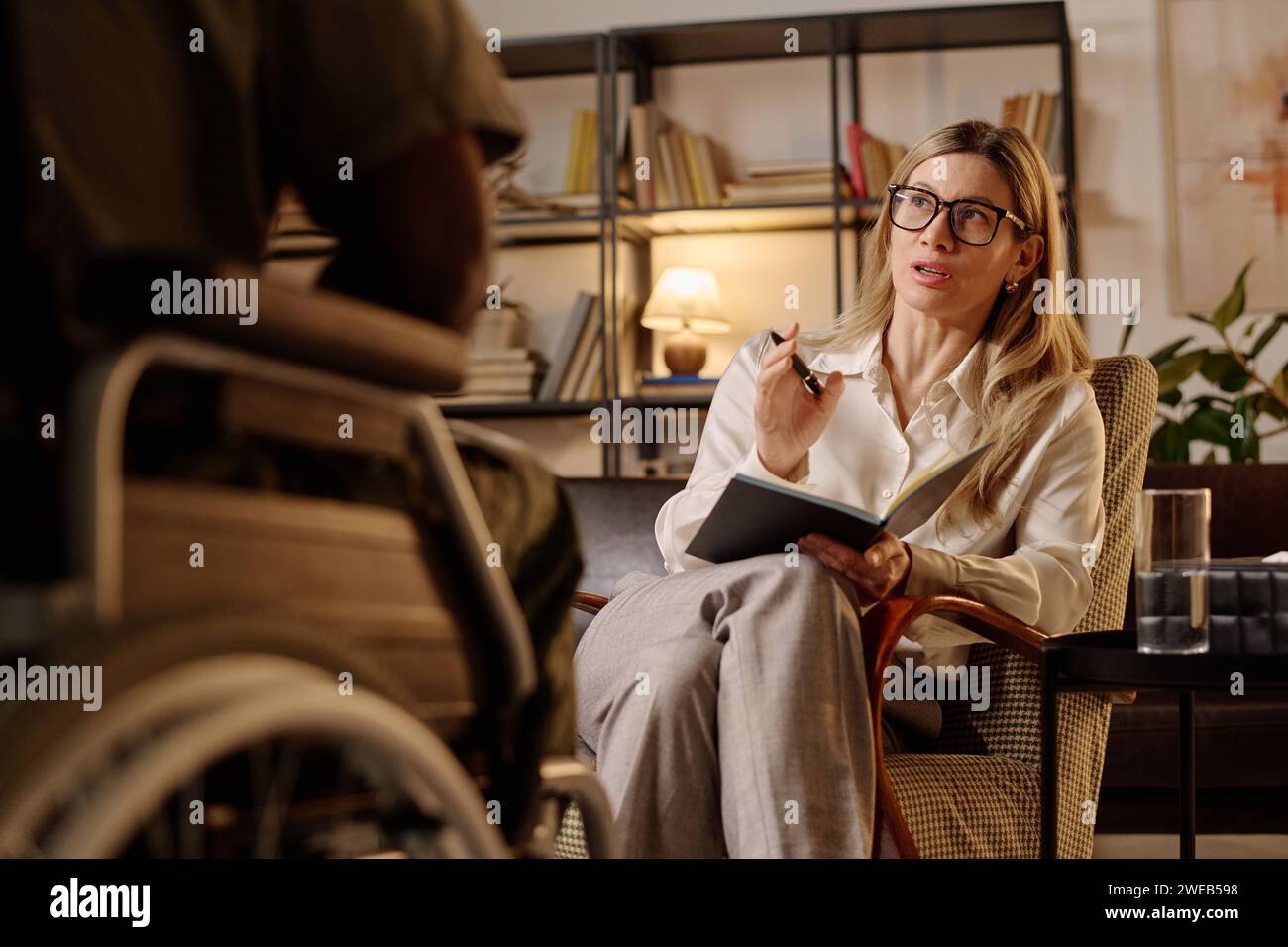 Professional psychologist sitting in armchair at her office and talking ...