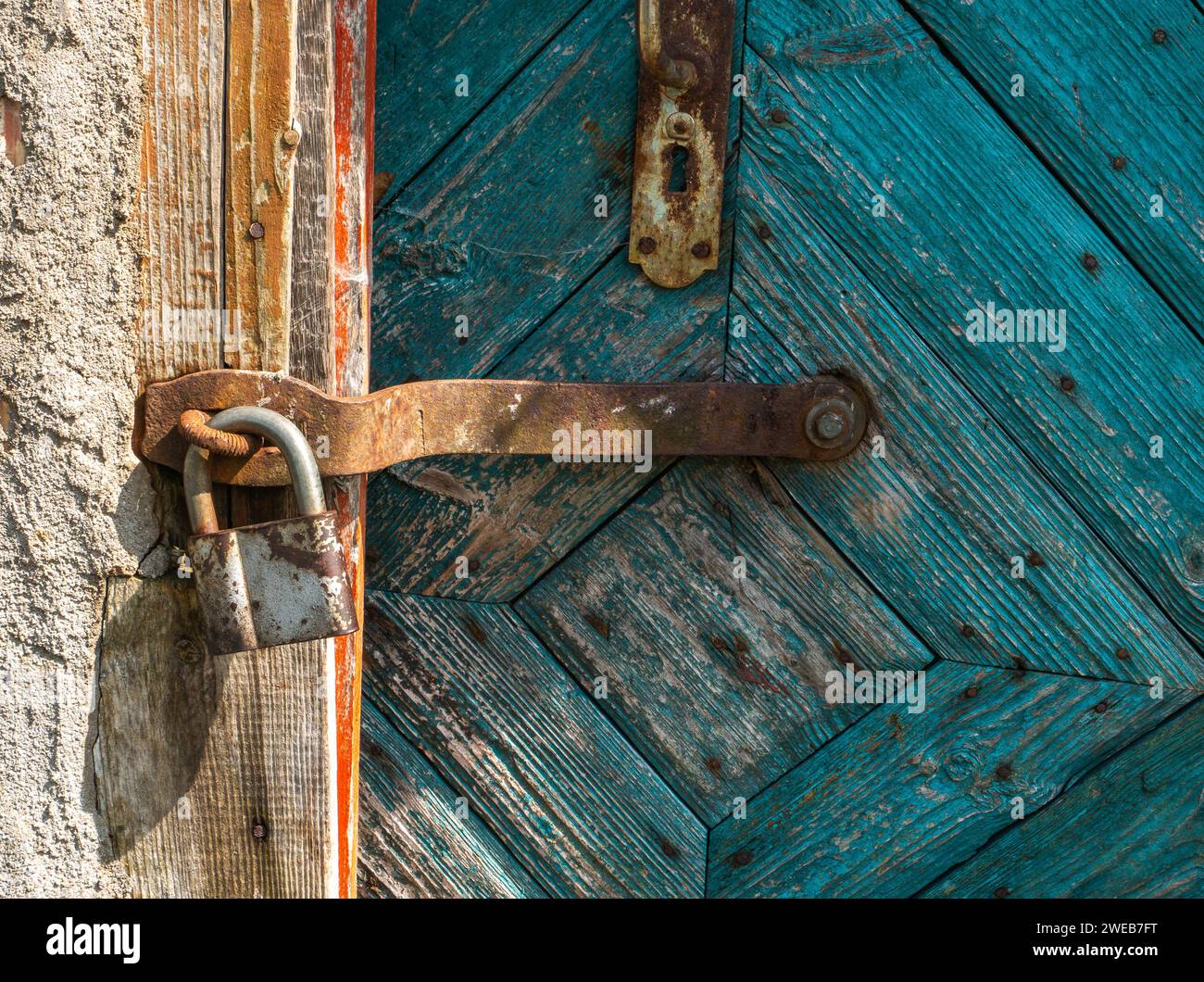 Close up of sliding bolt. Old rusty lock and latch on worn green wooden ...