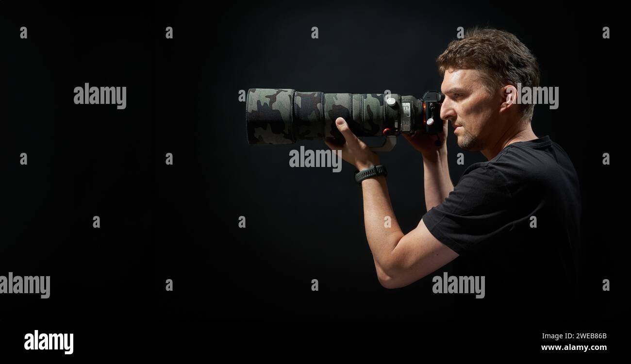 young photograph aiming with camera and big lens with attached lens ...