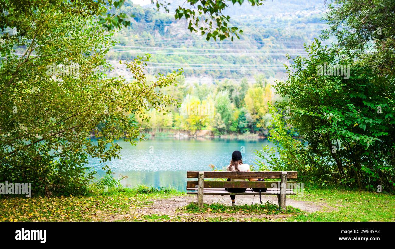 Woman sitting on a park bench in Switzerland while watching the lake ...