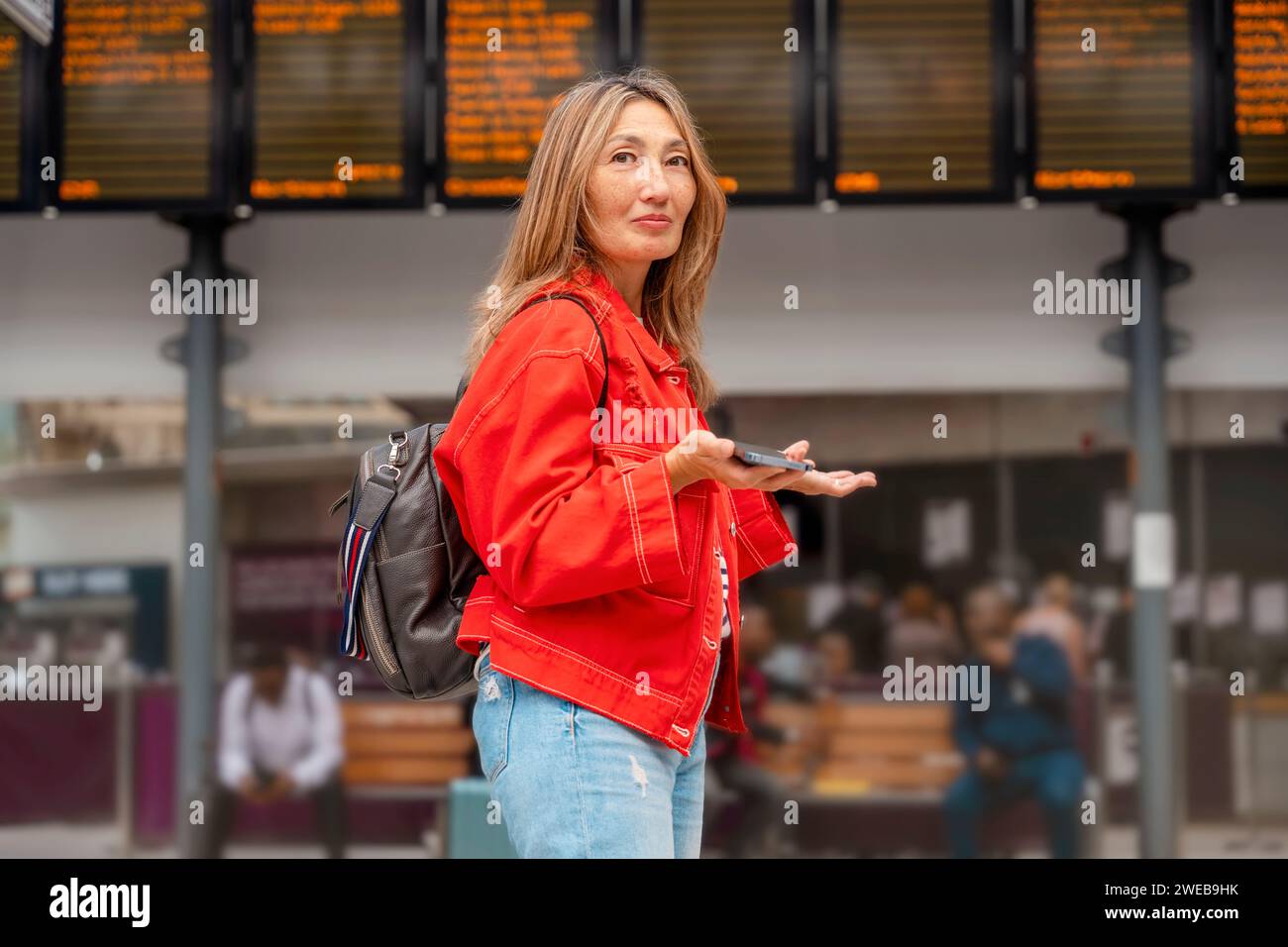 sad asian woman with backpack and holding smartphone while at the train ...