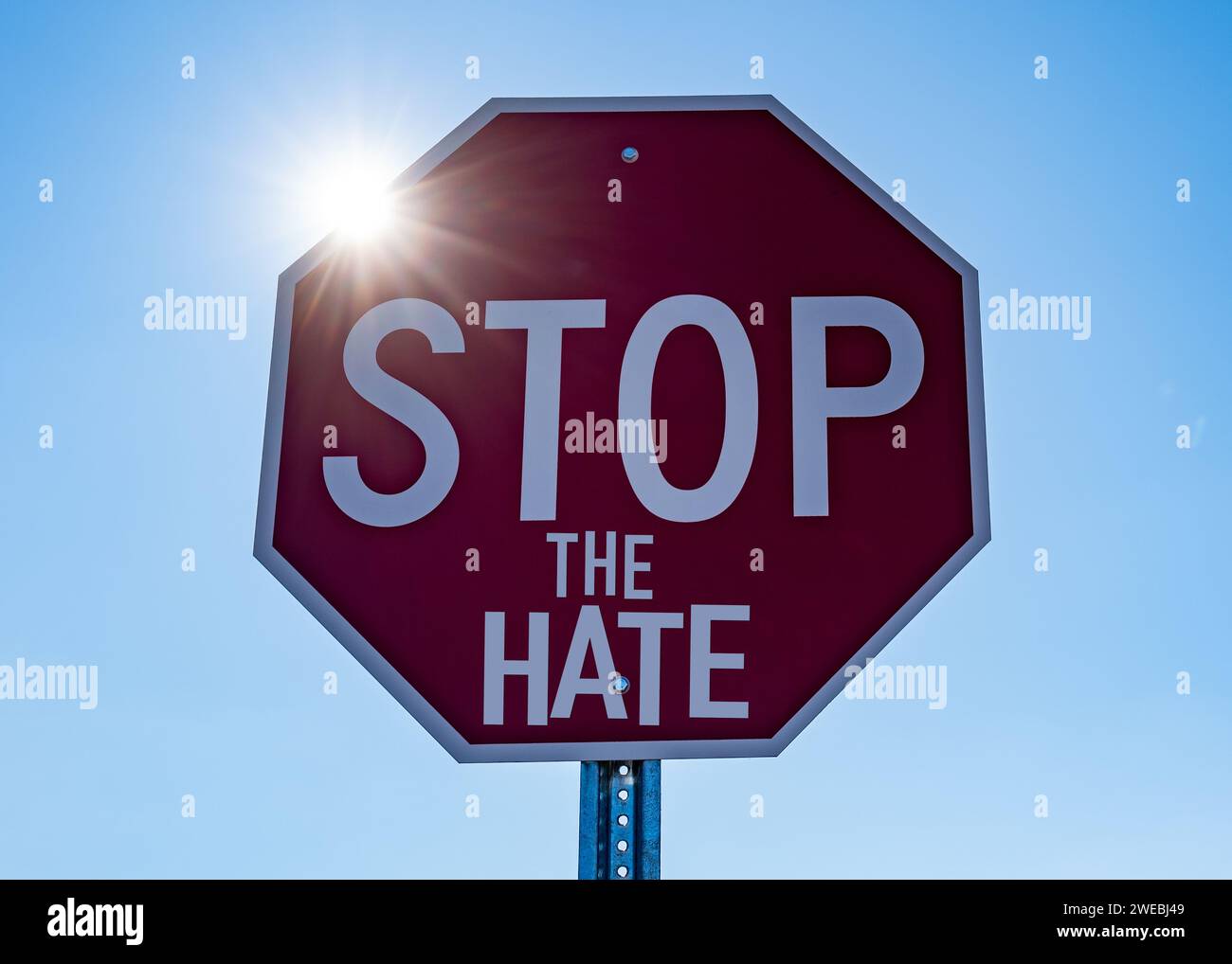 Photo of a red stop sign with sun shining over the edge saying stop the hate Stock Photo - Alamy