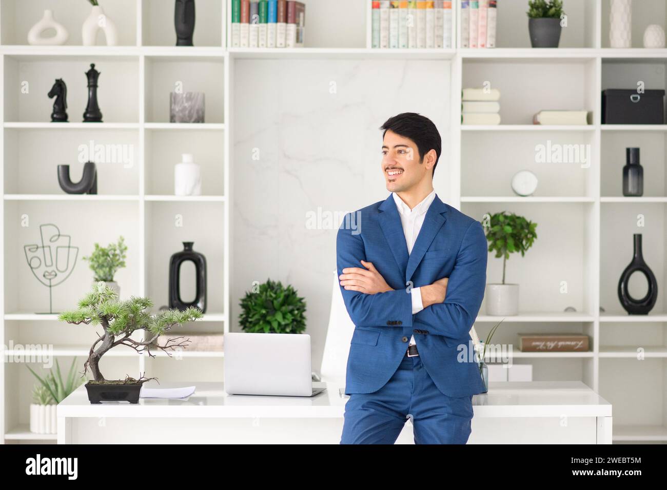 A thoughtful Hispanic businessman in a blue suit, contemplating while ...