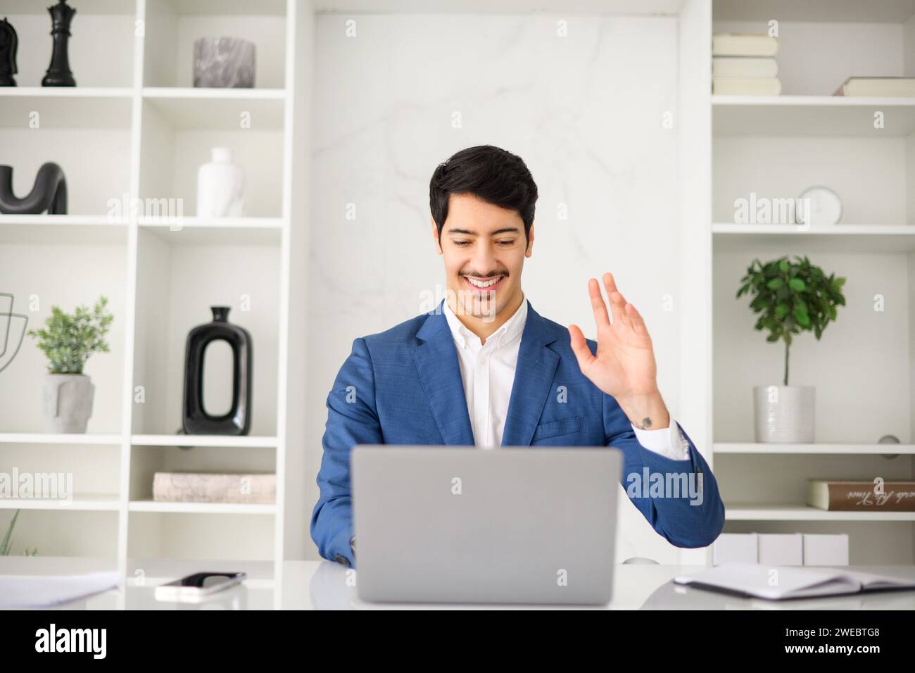 A charismatic Hispanic businessman makes a welcoming gesture during a ...