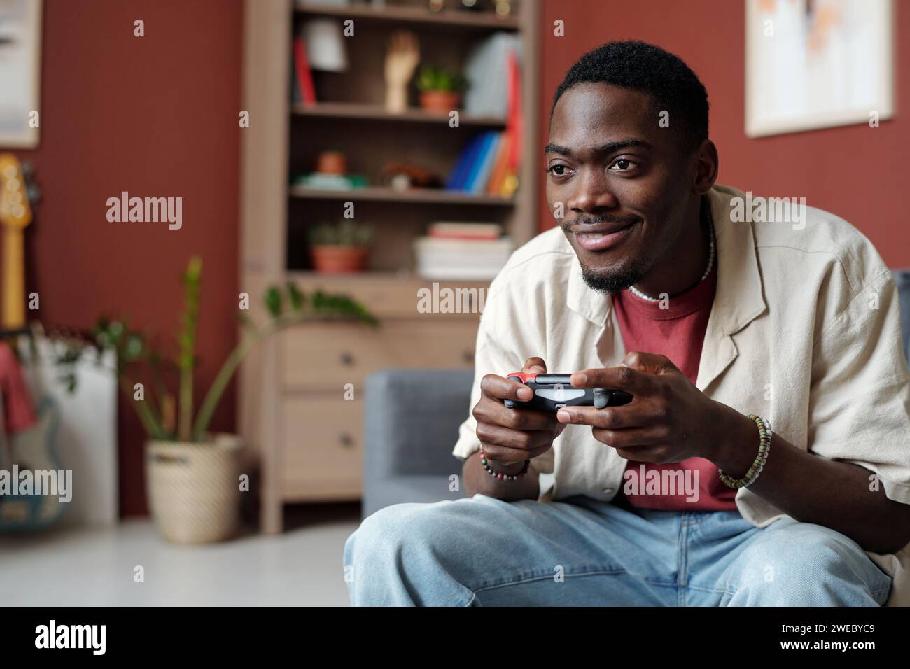 Smiling African American guy pressing buttons on controllers and ...