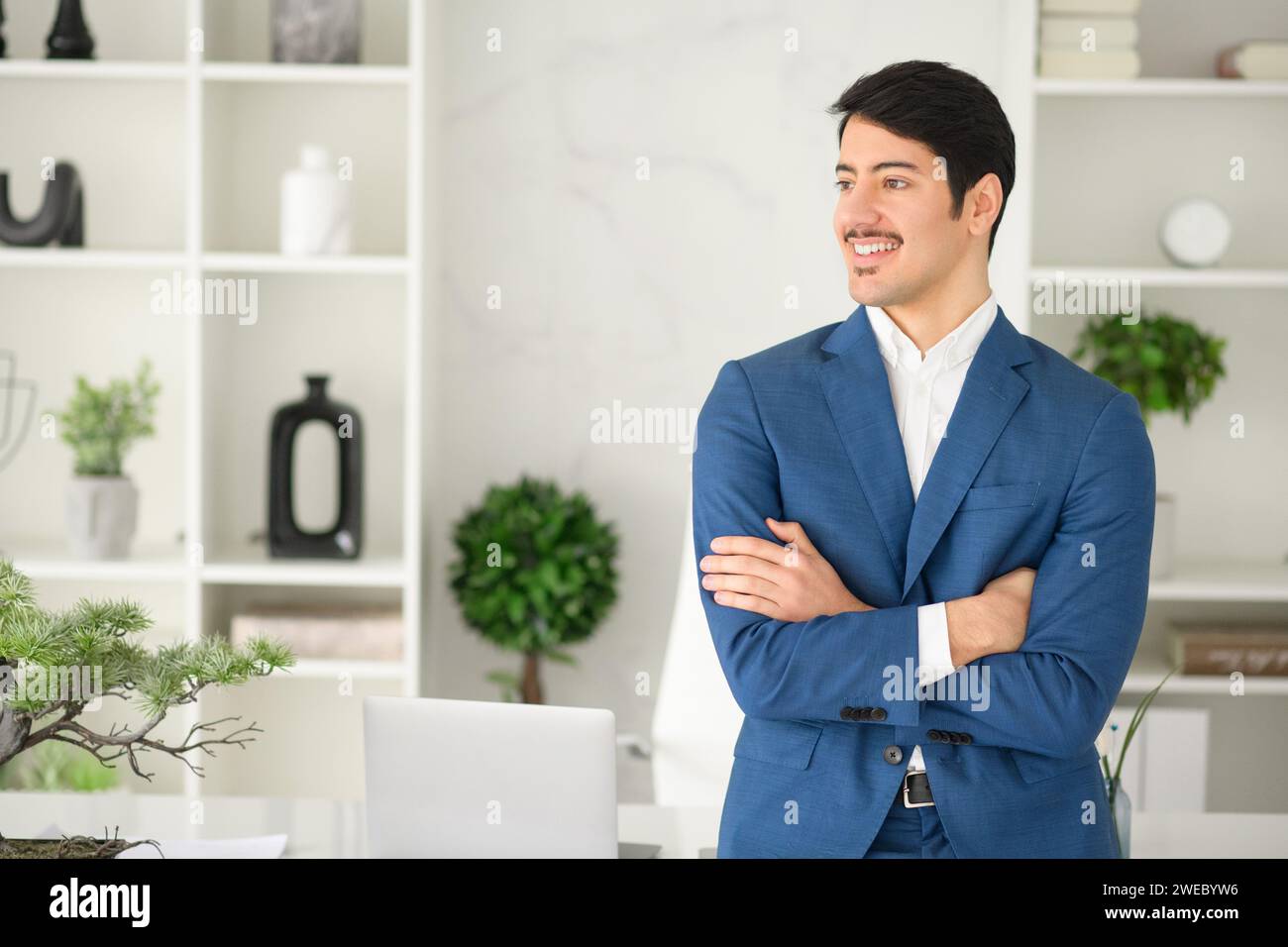 Young businessman smiling and standing in a relaxed pose with arms ...