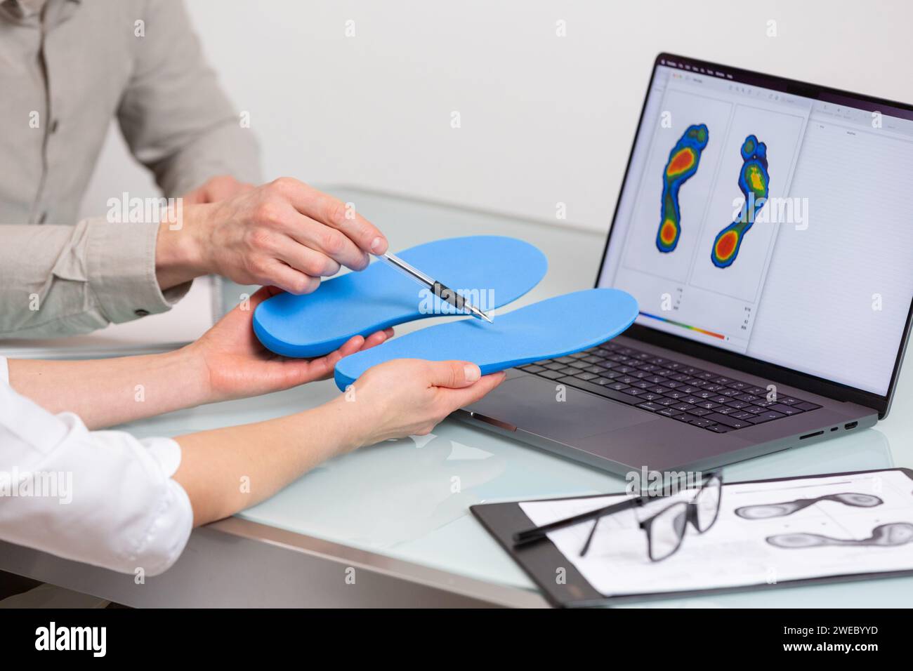Female doctor orthopedist gives custom insoles consultation to a male ...