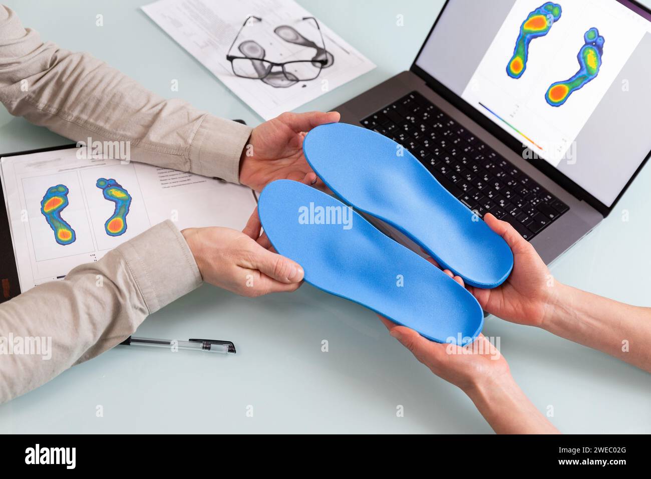 Female doctor orthopedist presents new custom made insoles to a male ...