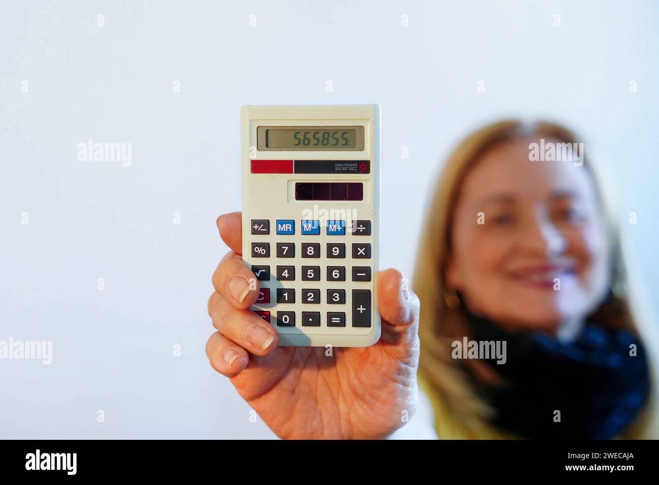 A senior woman showing the camera a white calculator Stock Photo - Alamy