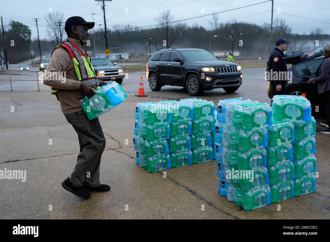 Volunteer Mike Harris works to help provided bottled water to residents ...