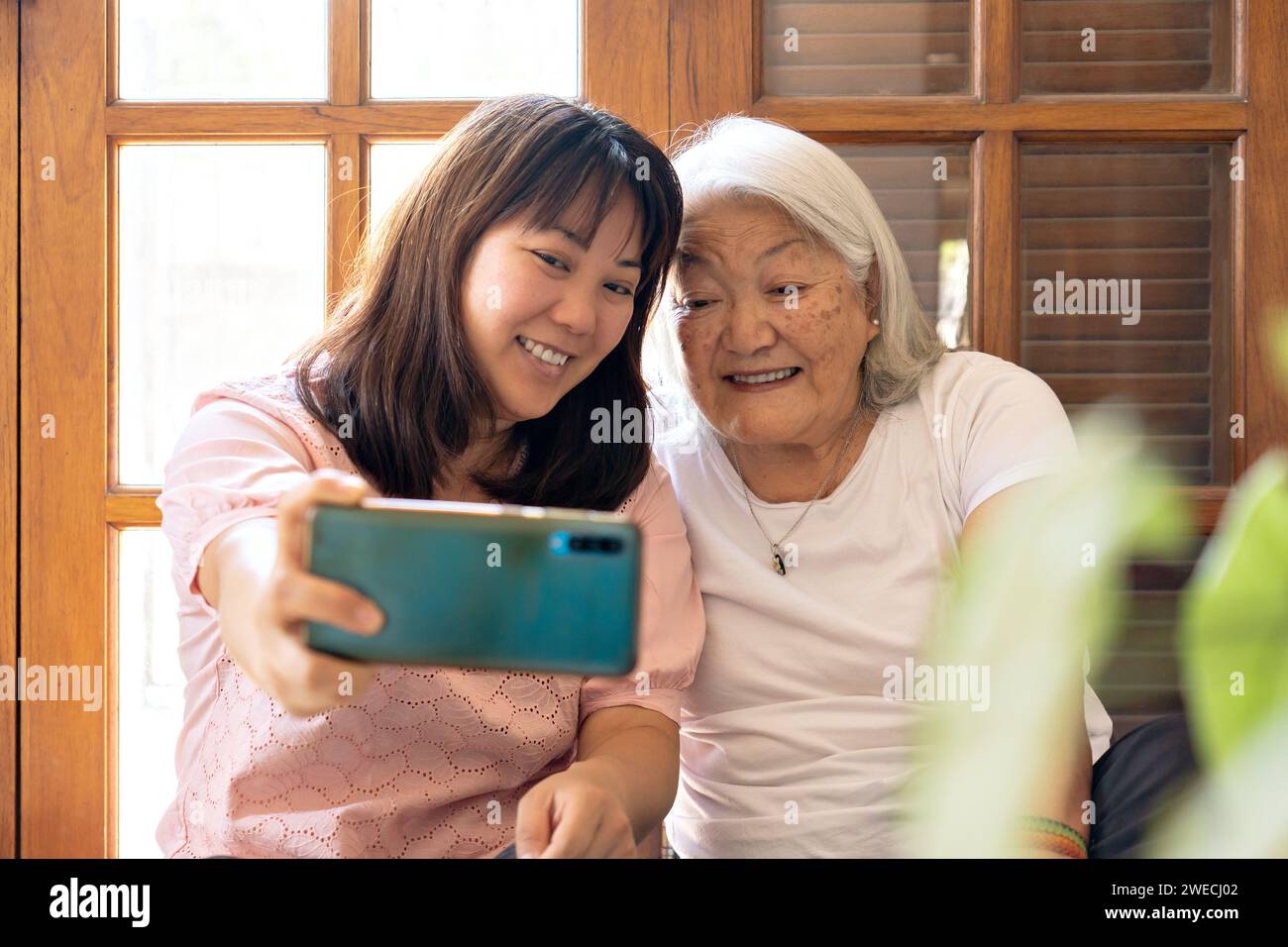 Loving daughter taking selfie using mobile phone with mother at home ...