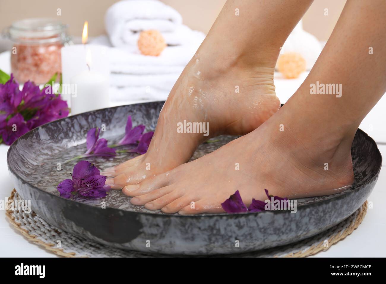 Woman pouring water onto her feet in bowl on floor, closeup. Spa ...
