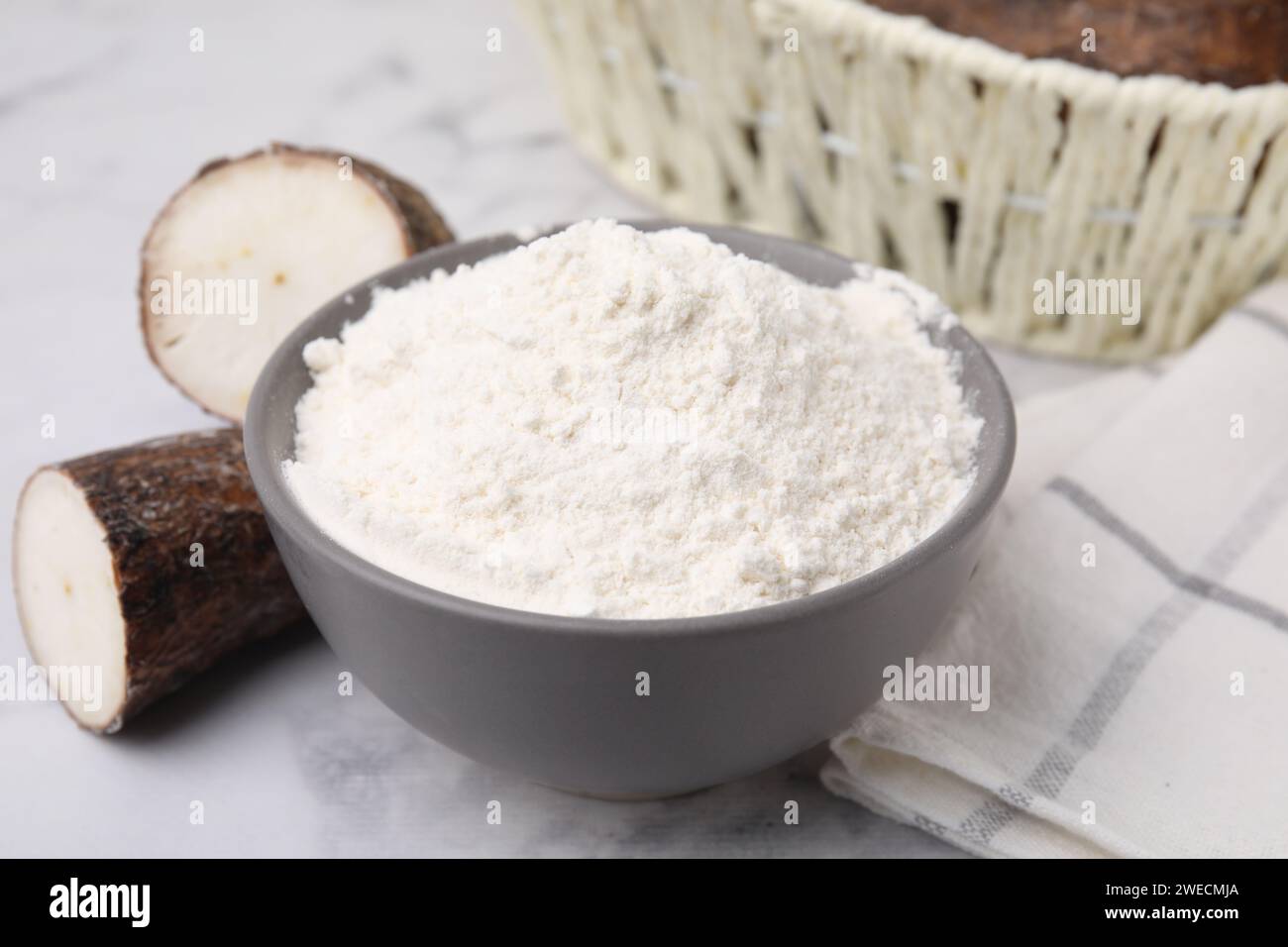 Bowl with cassava flour and roots on white marble table, closeup Stock ...