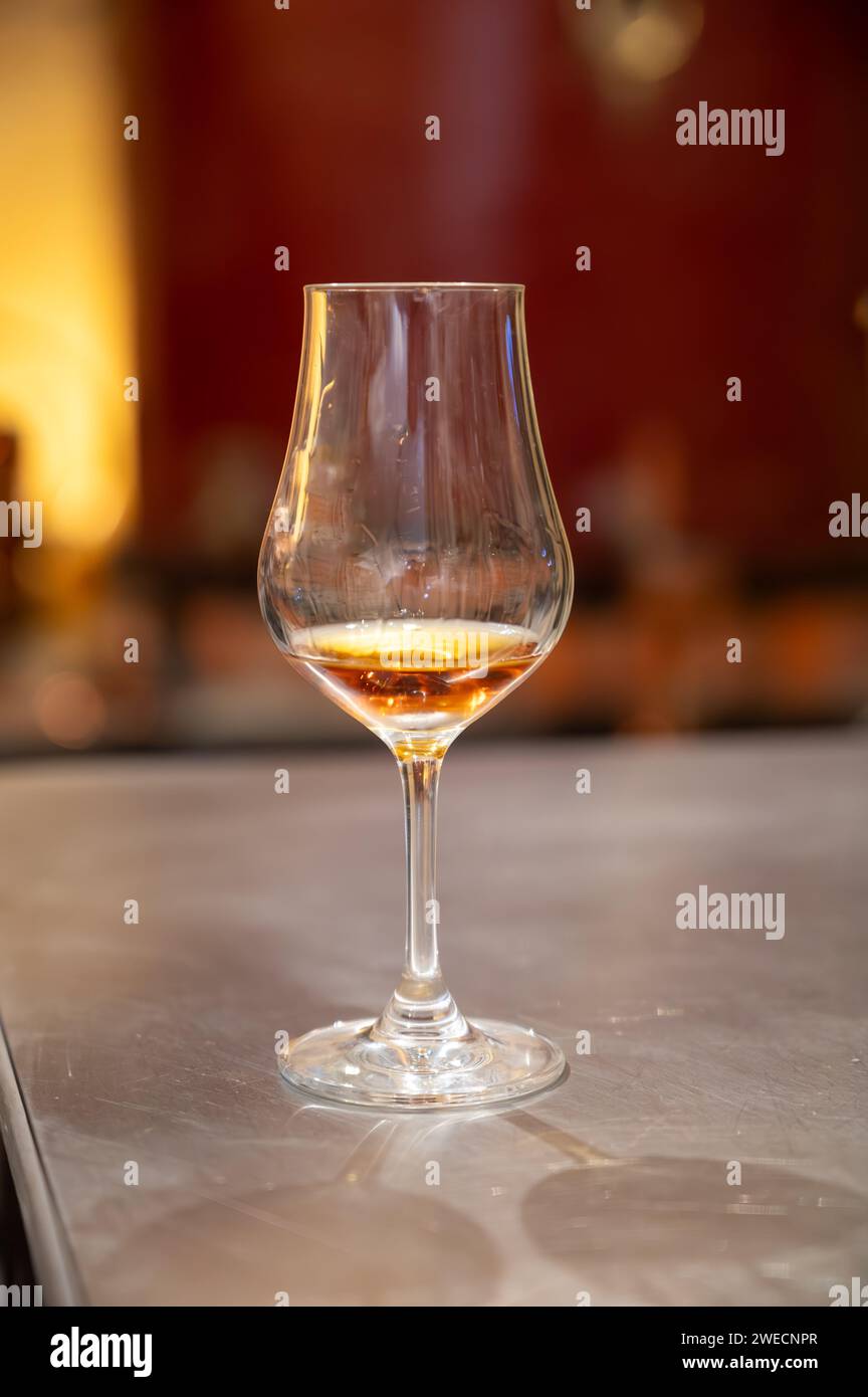 Tasting of cognac spirit aged in old dark French oak barrels in cellar ...