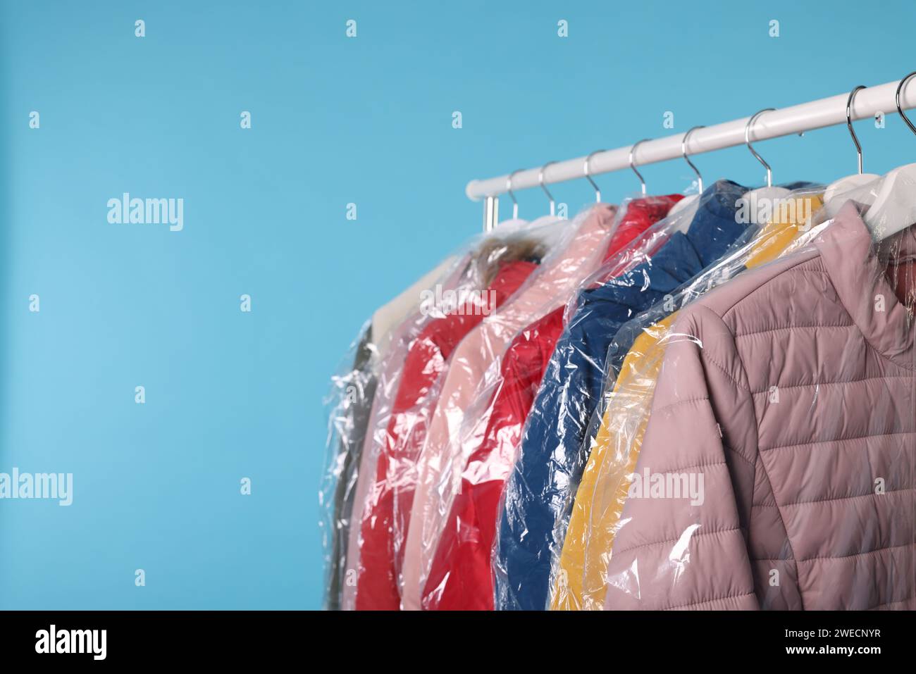 Dry-cleaning service. Many different clothes in plastic bags hanging on ...