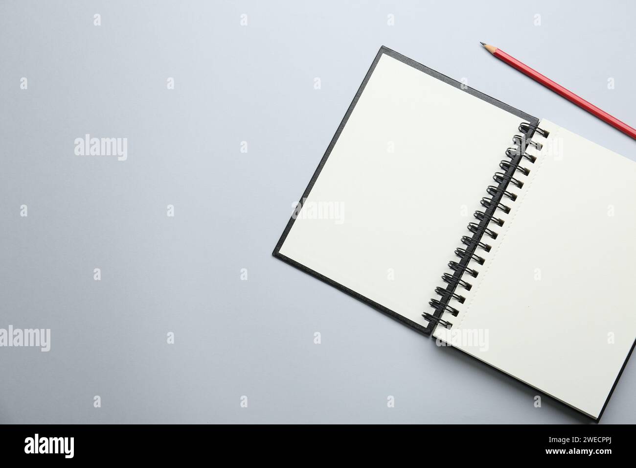 One notebook and pencil on light grey background, top view. Space for ...