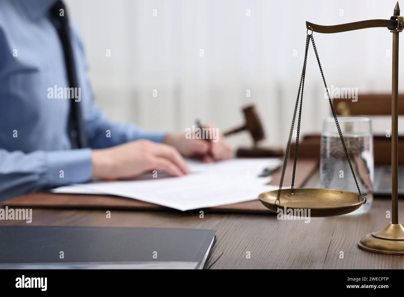 Lawyer working with documents at wooden table, focus on scales of ...